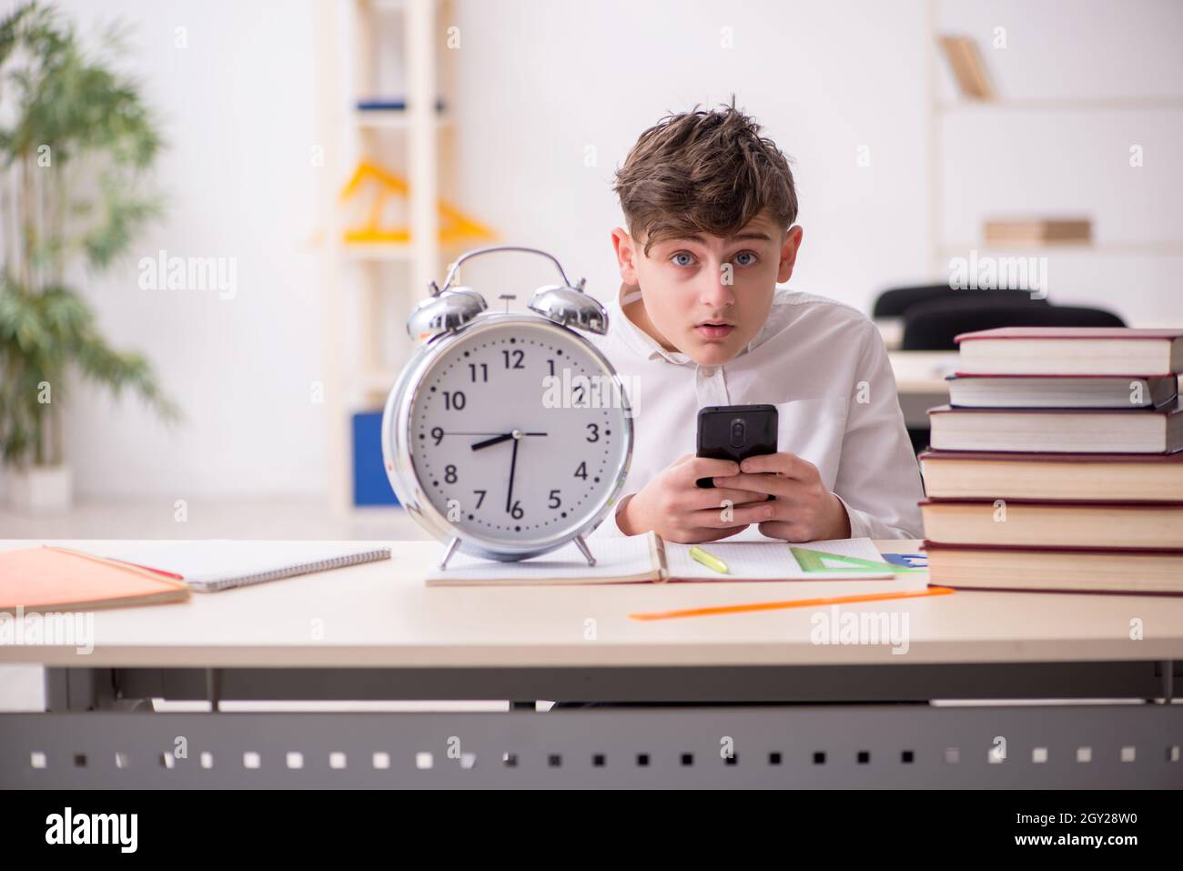 Schoolboy in time management concept in the classroom Stock Photo - Alamy