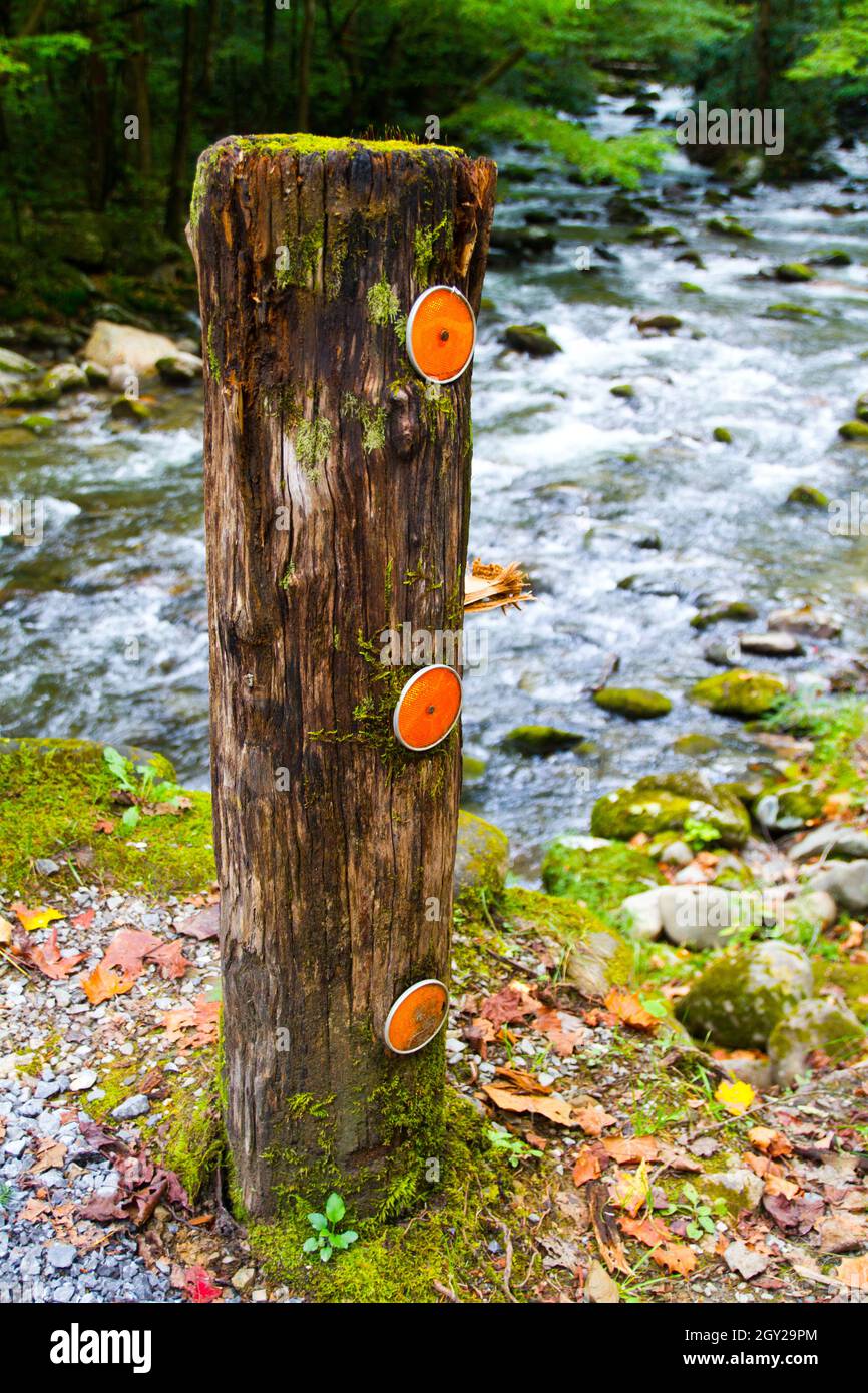 Vertical sign post with fluorescent orange markers stands in front of a ...