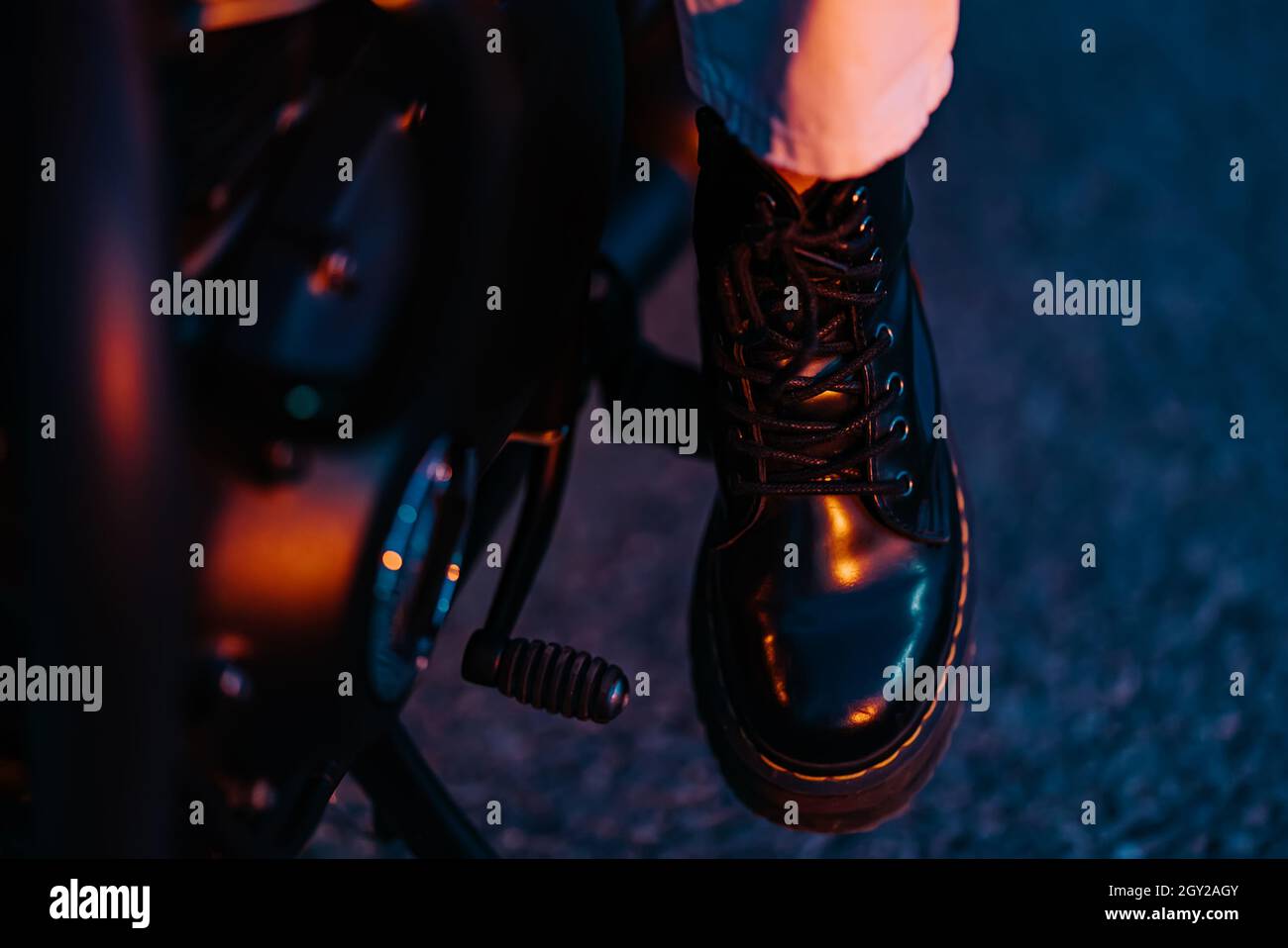 Legs of stylish motorcyclist woman sitting on classic bike. Black retro ...