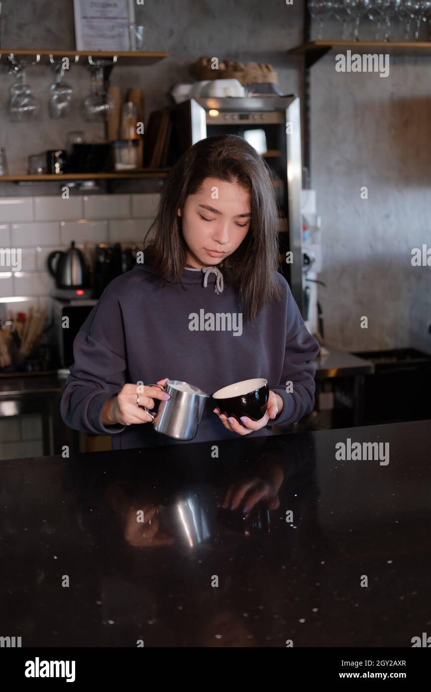 cute girl makes latte in coffee shop. Barista making coffee. Draws a ...