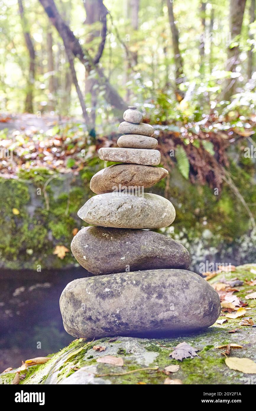 Serene stack of oval shaped rocks with trees and a river in the ...