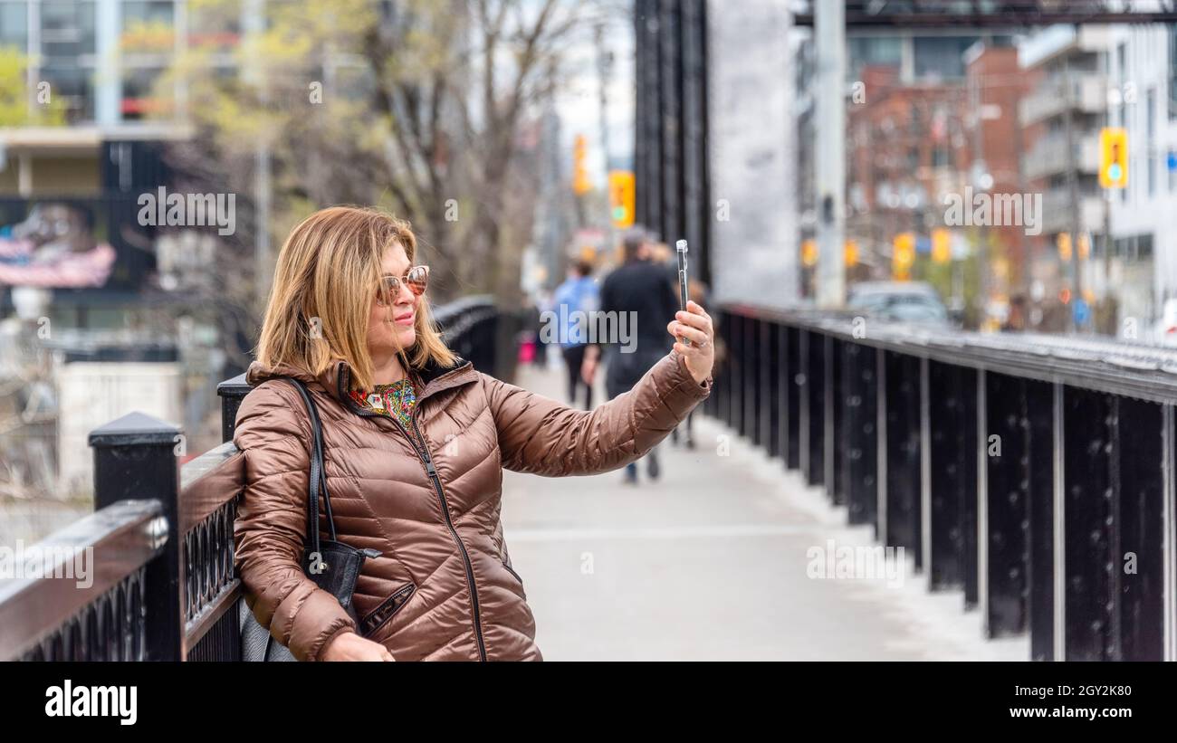 One Latin American woman taking a selfie in the Sir Isaac Brock Bridge ...