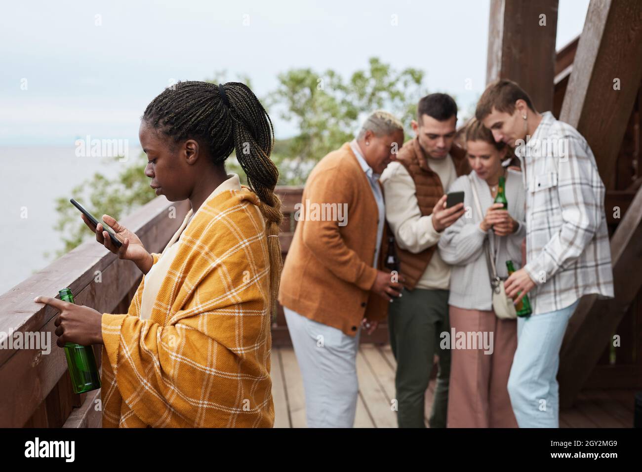 Diverse group young people relaxing on balcony during party at lake ...