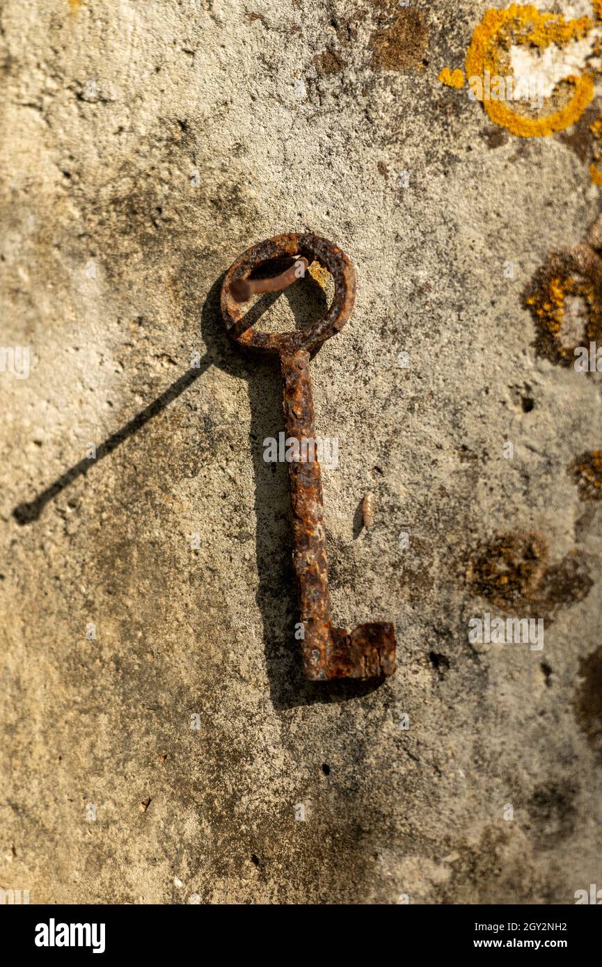 rusty old corroded key hanging on a wall on a rusty nail casting a ...