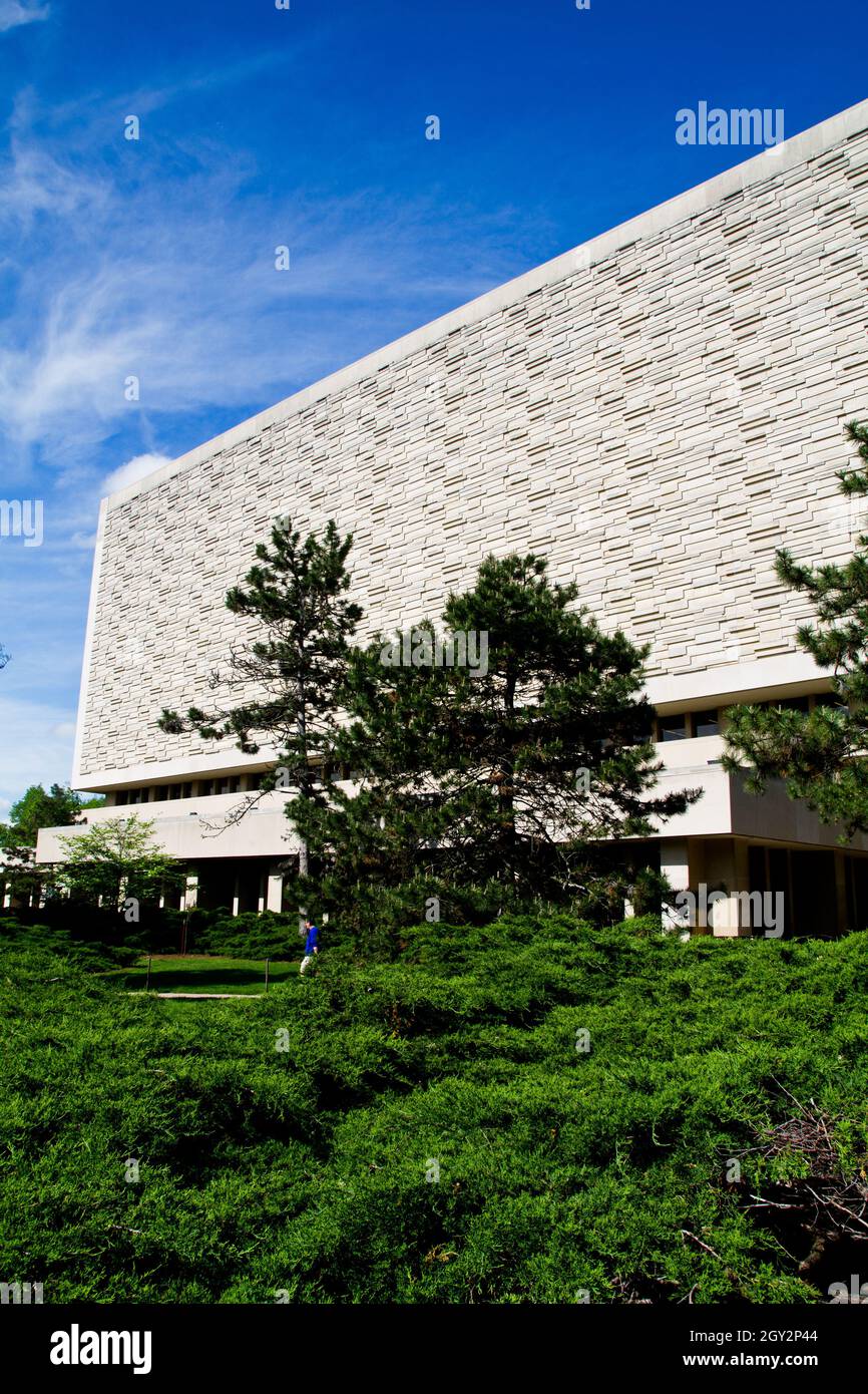 Tall white library building with trees and bushes in the foreground ...