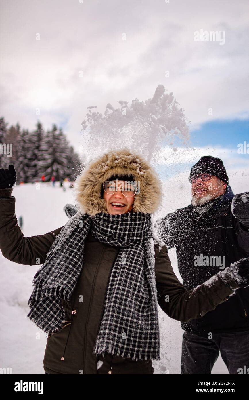young woman having fun in the snow smiling as snow is thrown towards ...