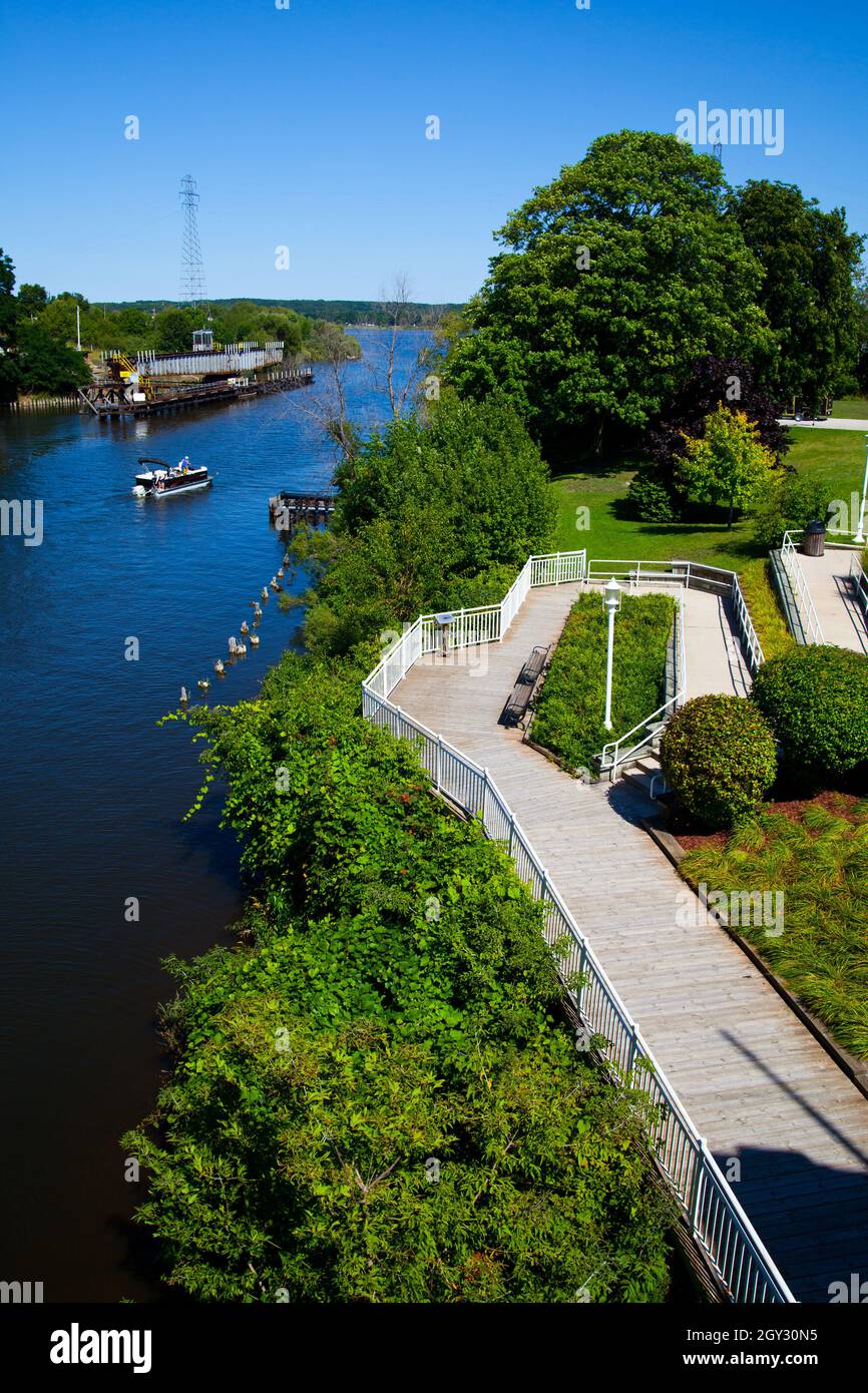 Wooden ramp going down between trees follows the blue river on a clear ...
