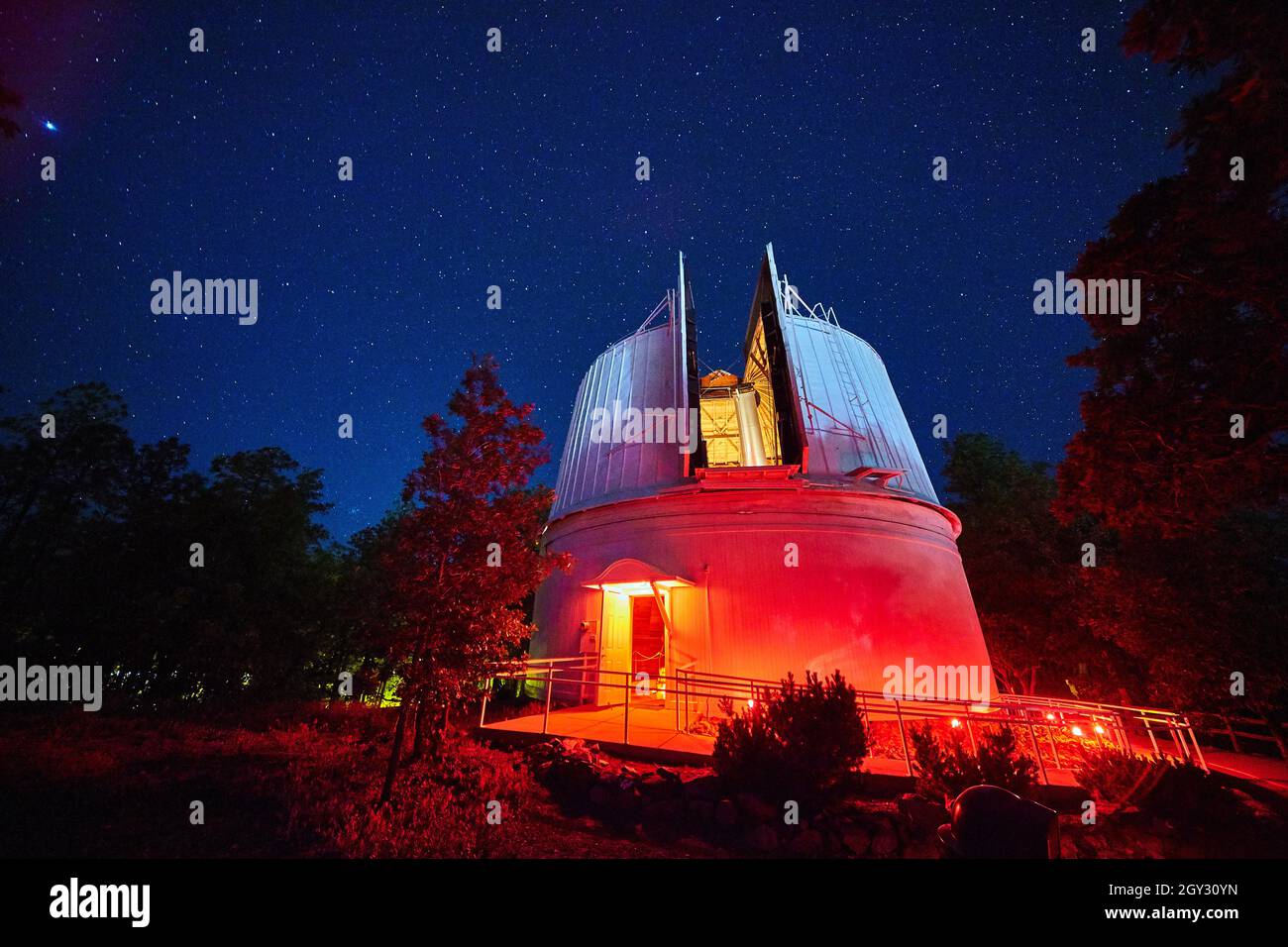 Observatory lit up in blue and red at night surrounded by trees Stock ...