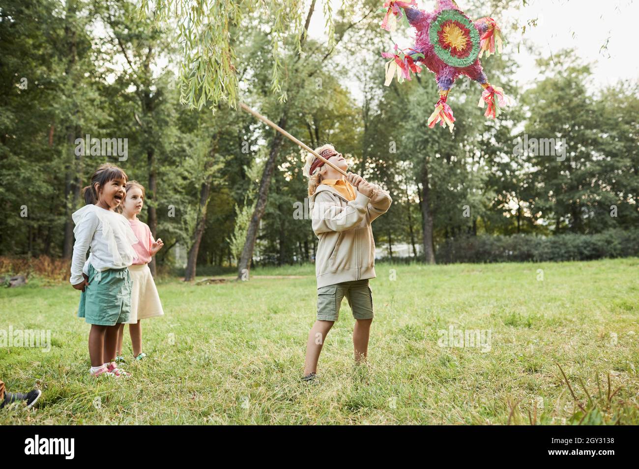 Full length portrait of boy playing pinata game at Birthday party ...