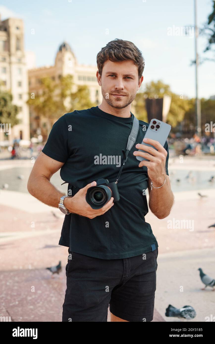 Trendy young male tourist in casual outfit, standing on square with ...