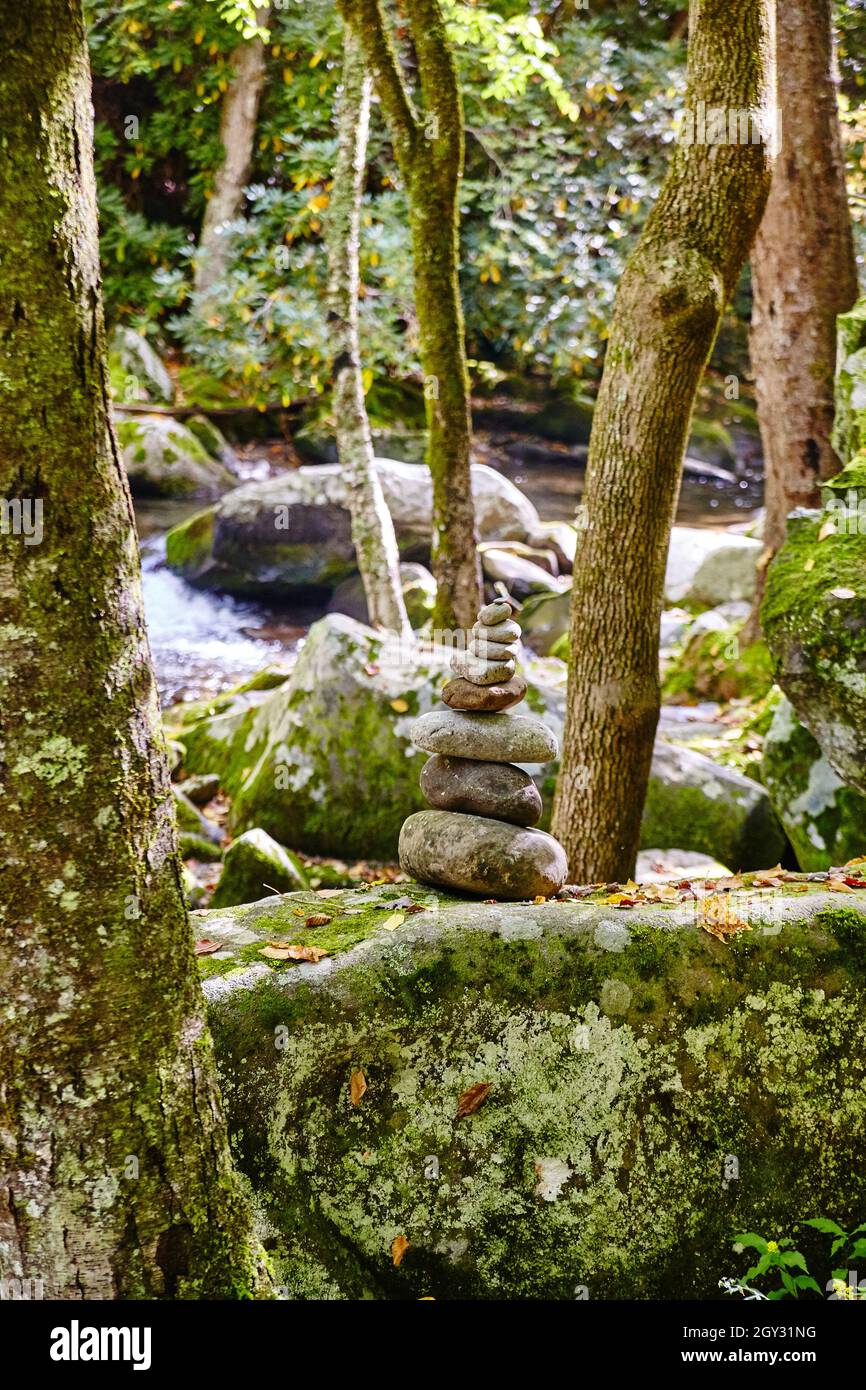 Rounded stack of rocks with trees in the foreground and a running river ...