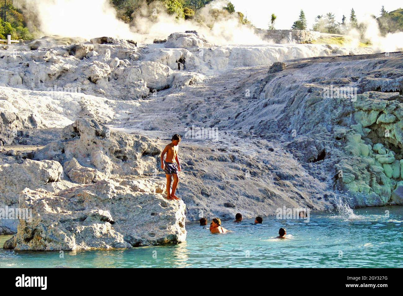 Maori swim in the blue waters at the base of Pohutu Geyser in Rotorua ...