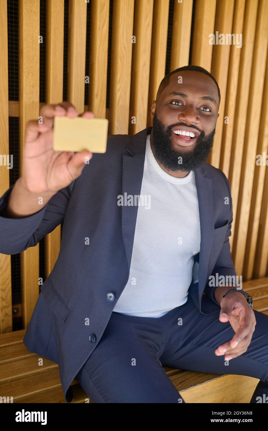 A bearded dark-skinned smiling man holding a credit card Stock Photo ...