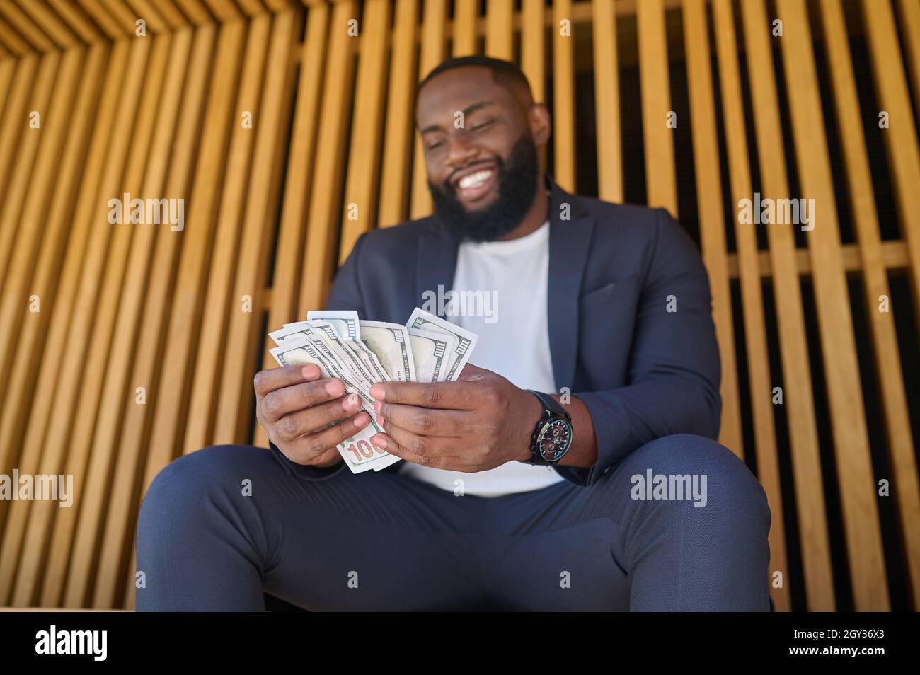 A man sitting on the bench and holding dollars in hands Stock Photo - Alamy