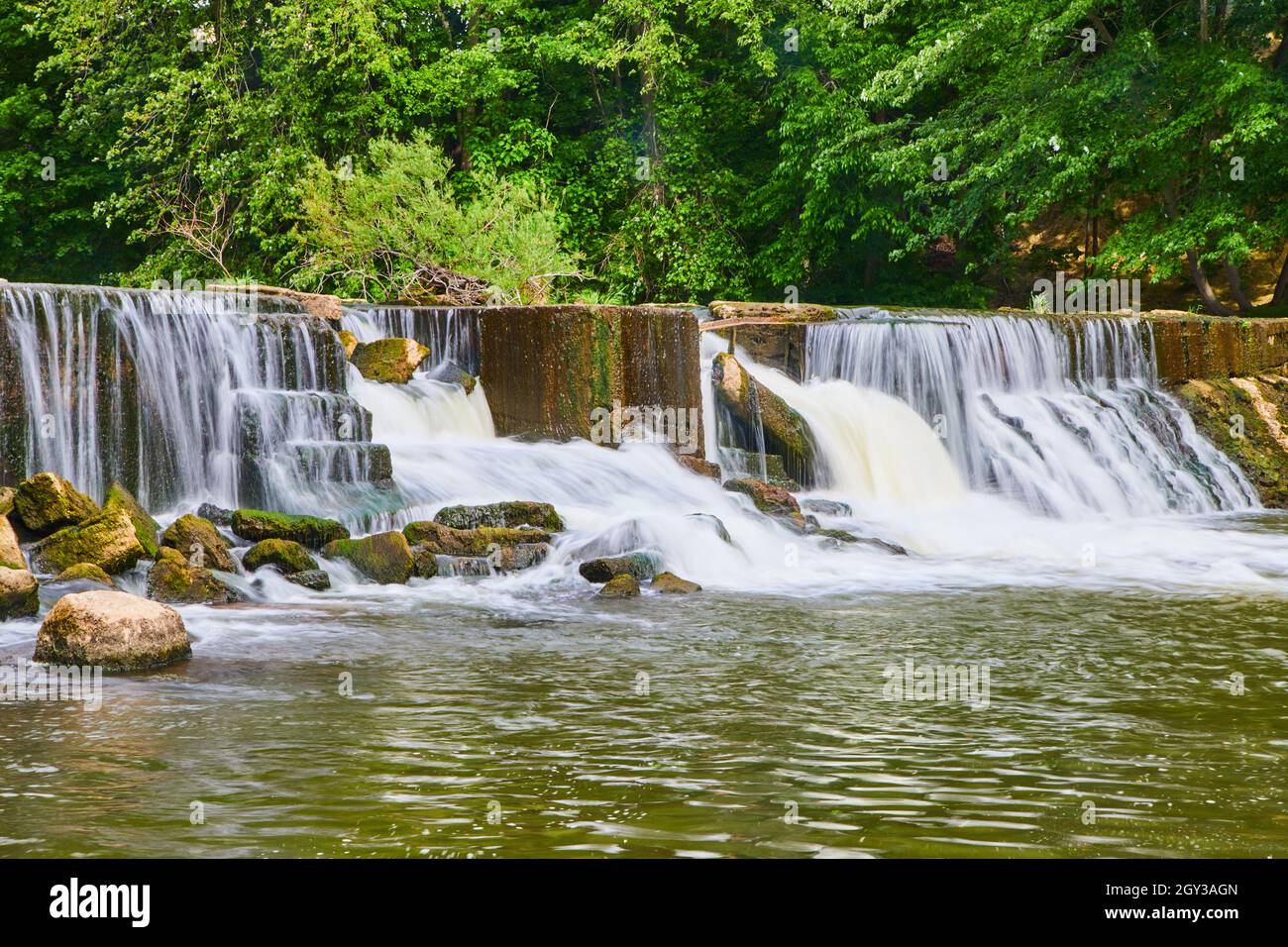 Dam with manmade waterfalls and background of green forest Stock Photo ...