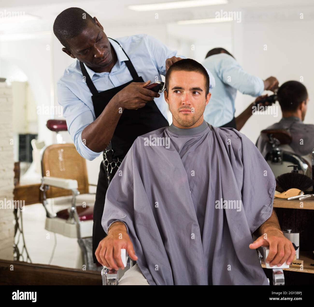 Man getting haircutting by African barber Stock Photo - Alamy
