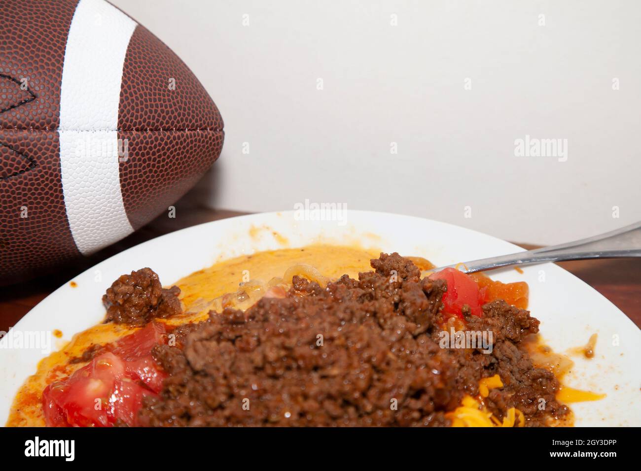 Spicy ground beef on a white plae with diced tomatoes and shredded ...