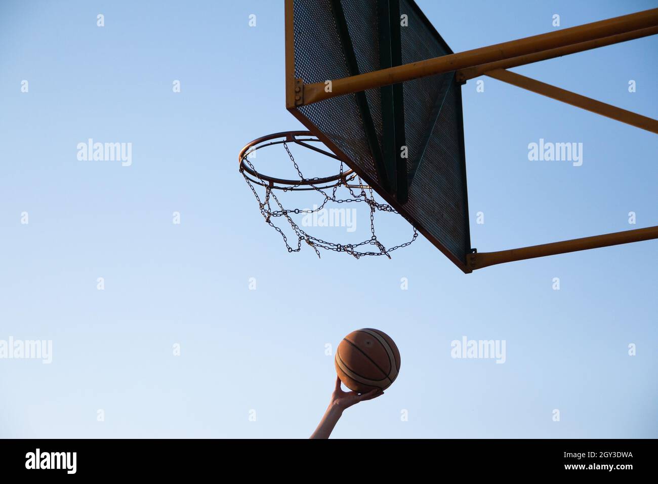 Basketball player's hand throwing basketball ball into the basket under ...