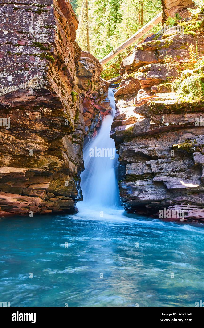 Steep cliffs covered in lichen with waterfall and blue water Stock ...