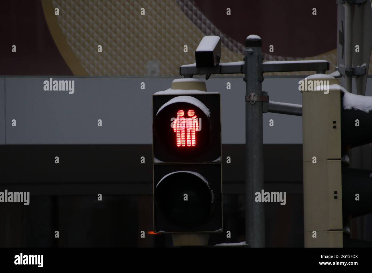 A red pedestrian crossing light depicting to males waiting to walk ...