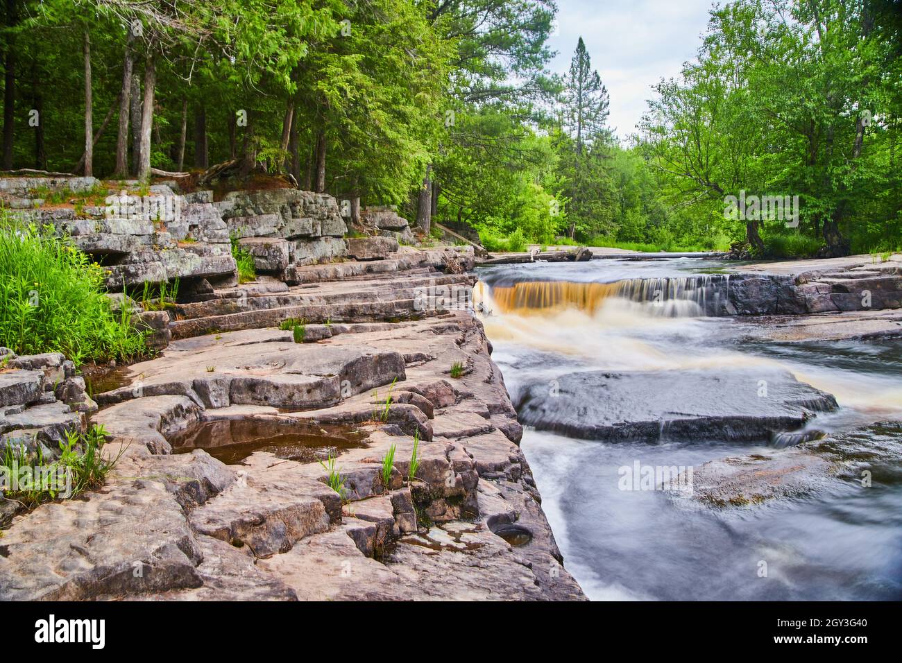 Waterfall creating small gorge with tiers of grey rocks in forest Stock ...