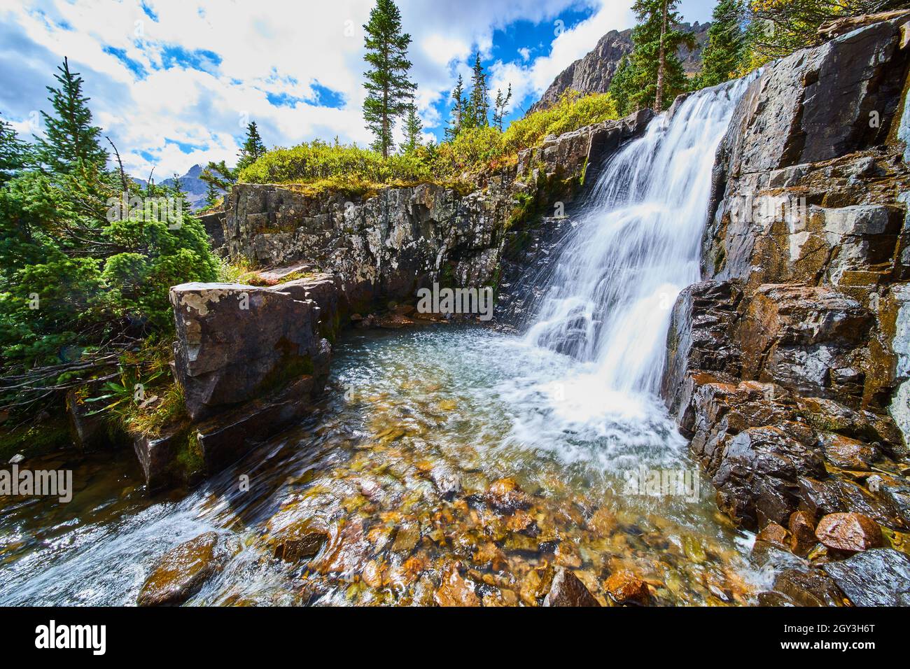 Majestic waterfall into bucket of water surrounded by rocks covered in ...