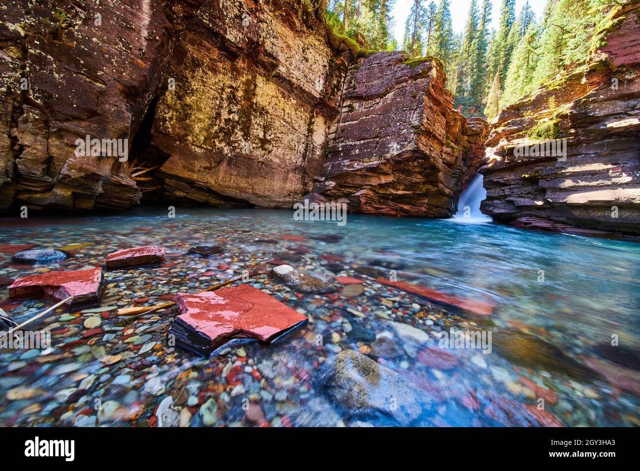 Red and blue river rocks in shallow river at bottom of gorge with ...