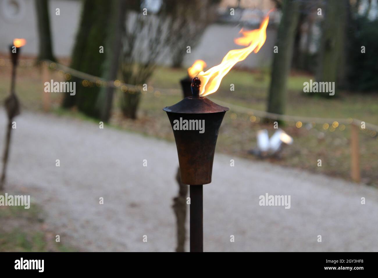 A flaming torch on the side of a gravel path Stock Photo - Alamy