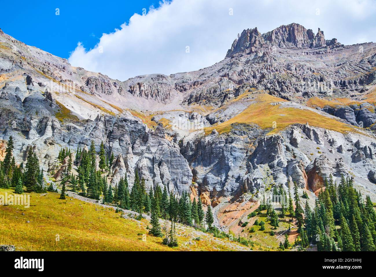 Mountain with columns of gray rock and sharp peaks with pine trees at ...