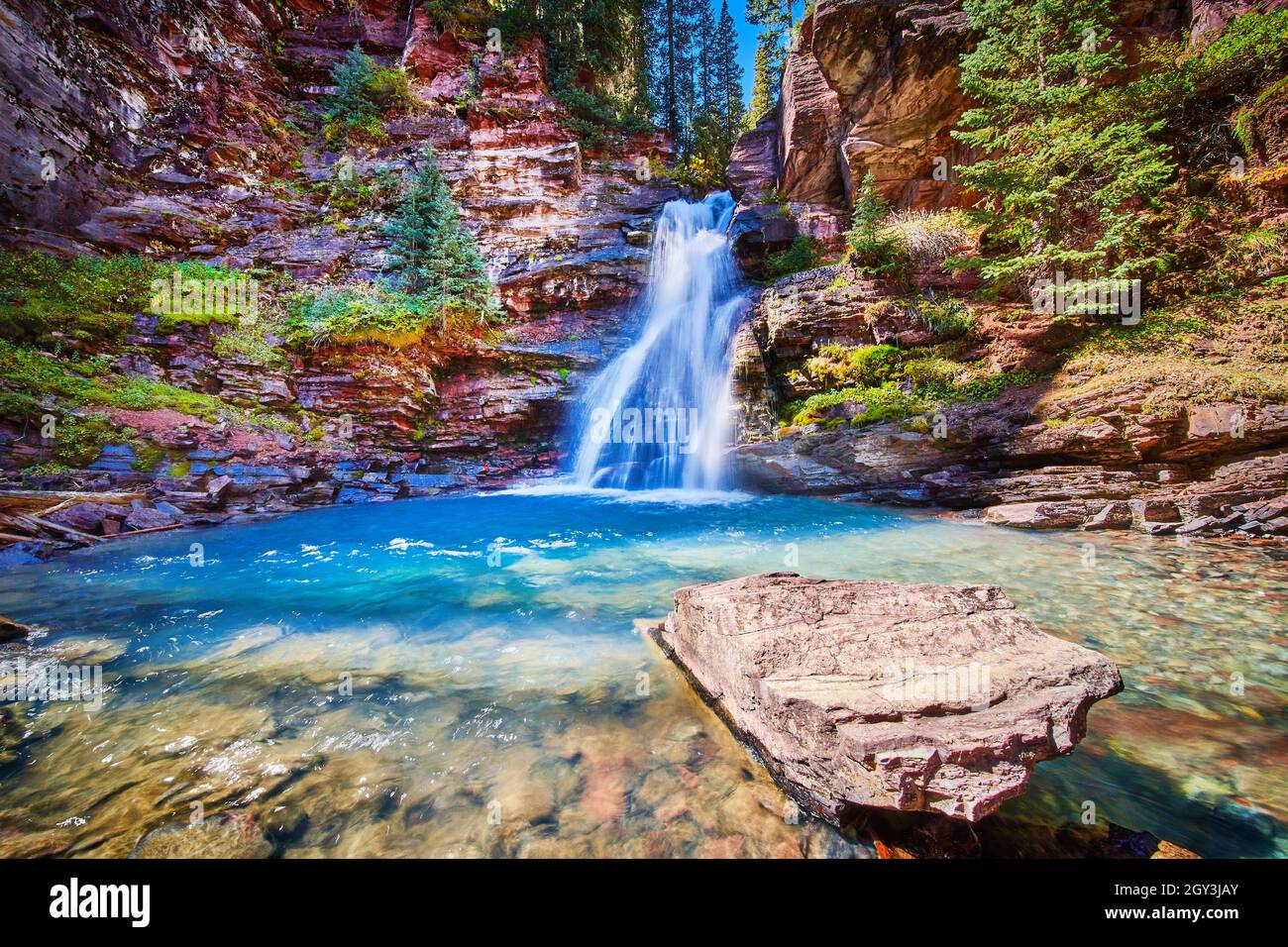 Sunny river of blue next to large waterfall tucked into canyon Stock ...