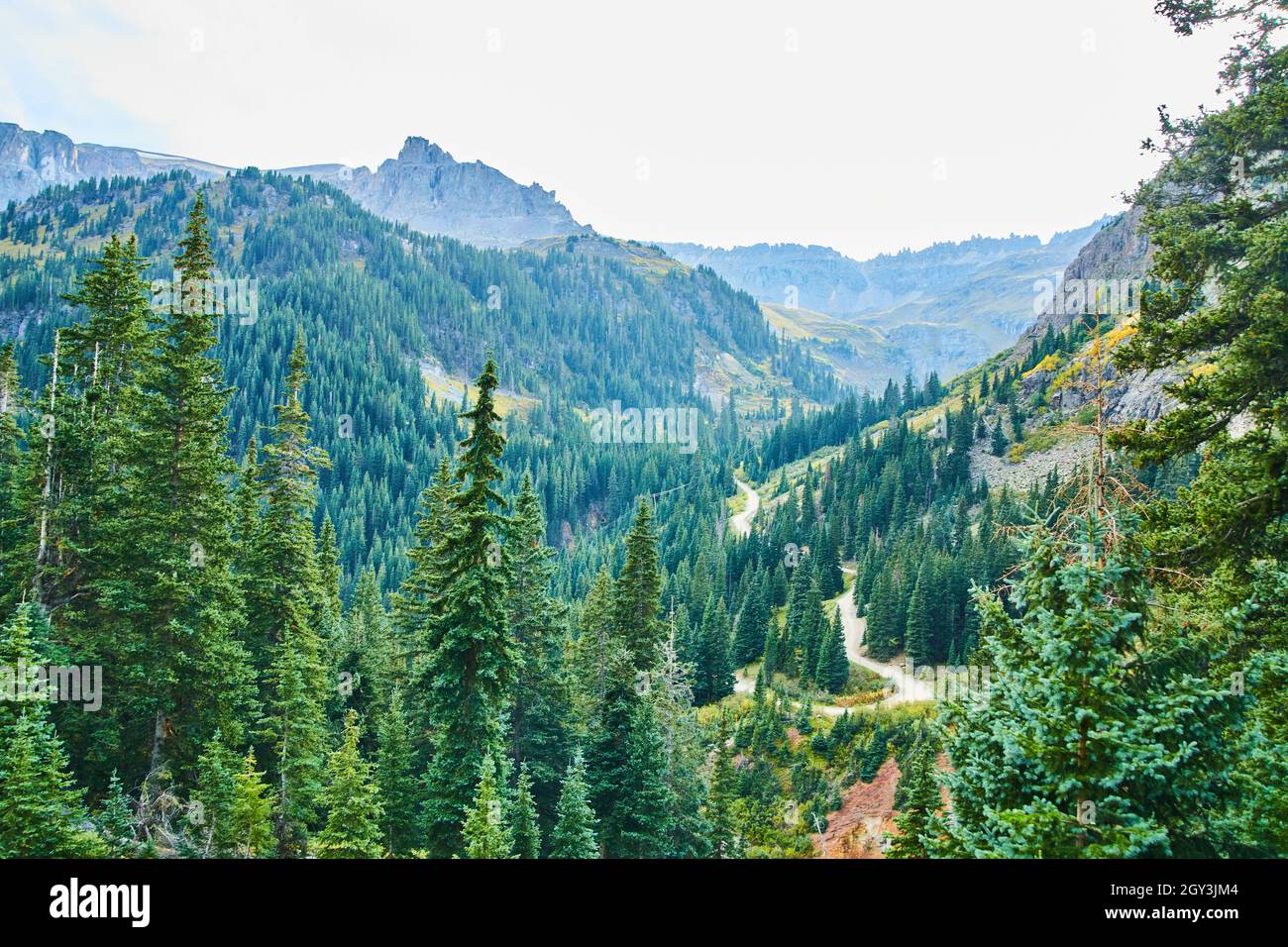 Dirt road winding through the valley of mountain ranges filled with ...