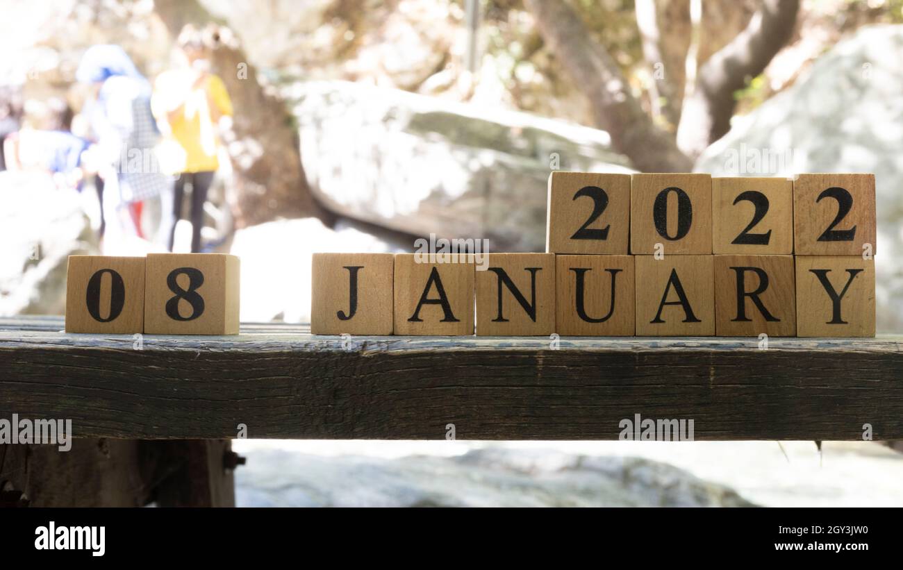 January was created from wooden cubes. Outdoors on table, trees in ...