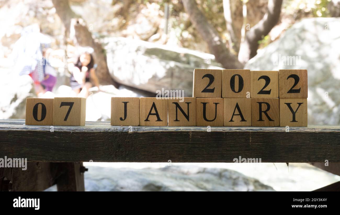 January was created from wooden cubes. Outdoors on table, trees in ...