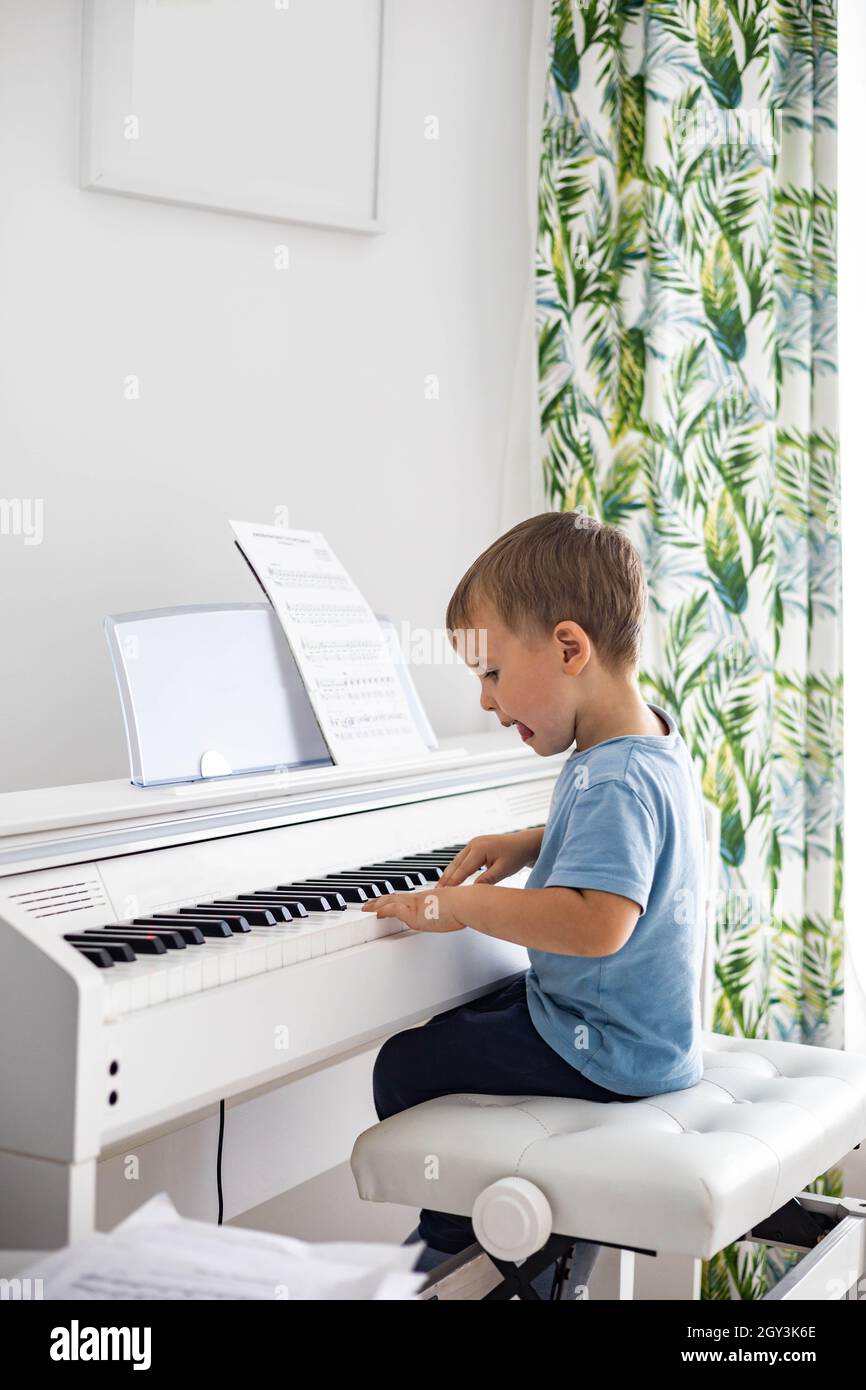 Cute baby boy playing white electrical forte piano pressing keys kid ...