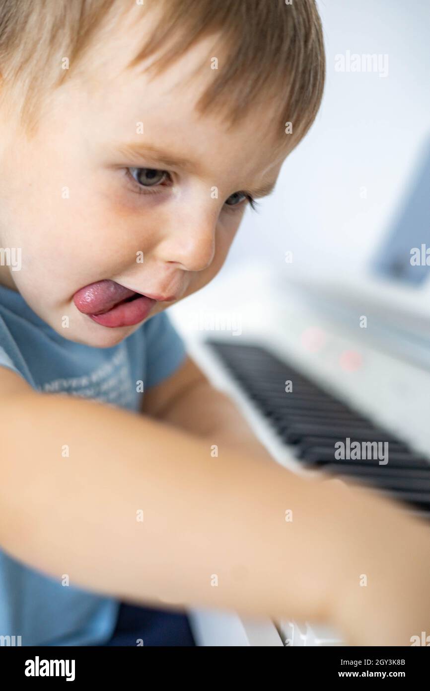 Cute baby boy playing white electrical forte piano pressing keys kid ...