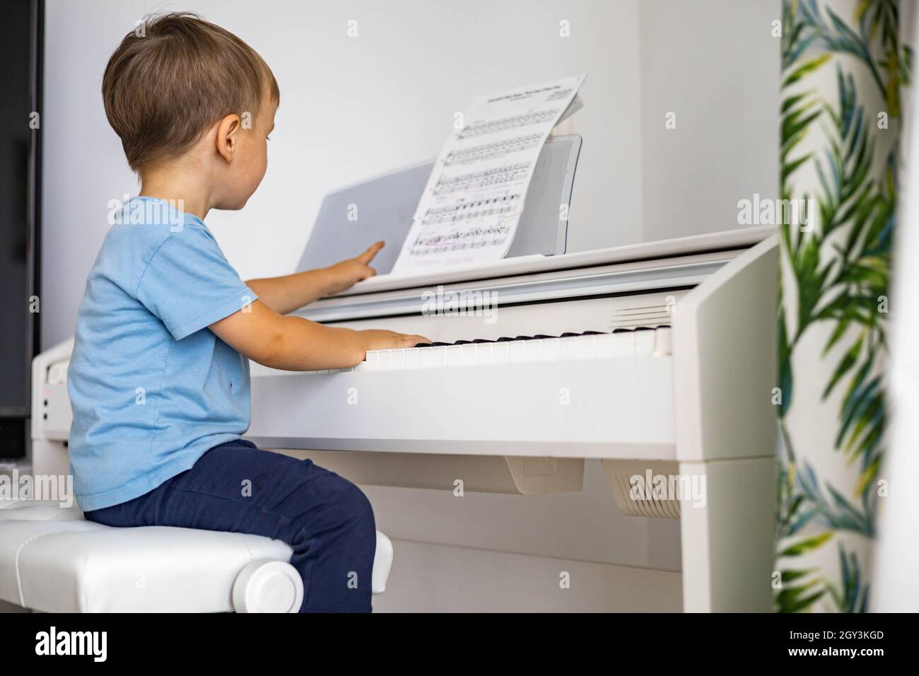 Cute baby boy playing white electrical forte piano pressing keys kid ...