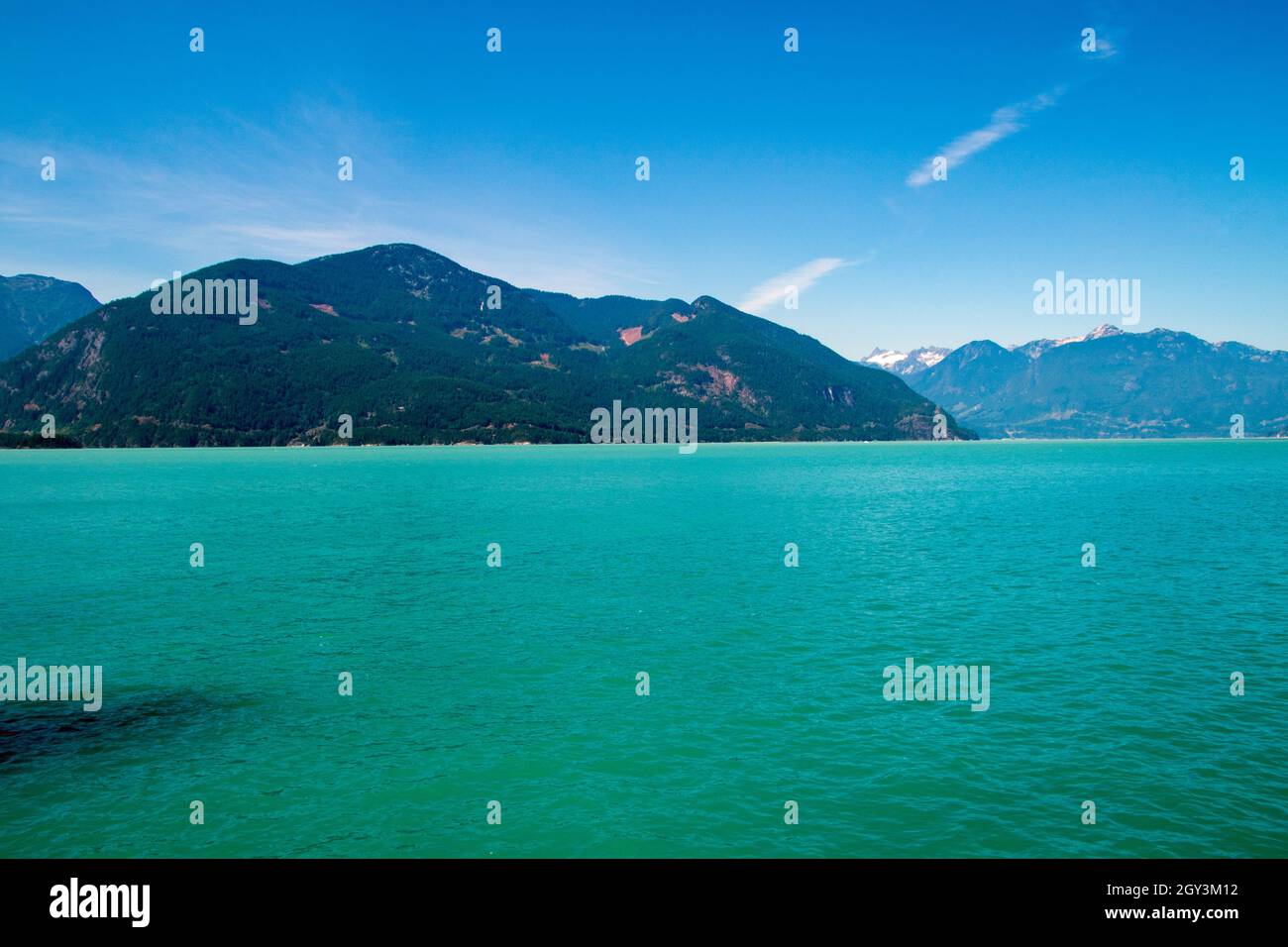 A view of green-blue water of a harbor with hills and mountains in the background Stock Photo ...