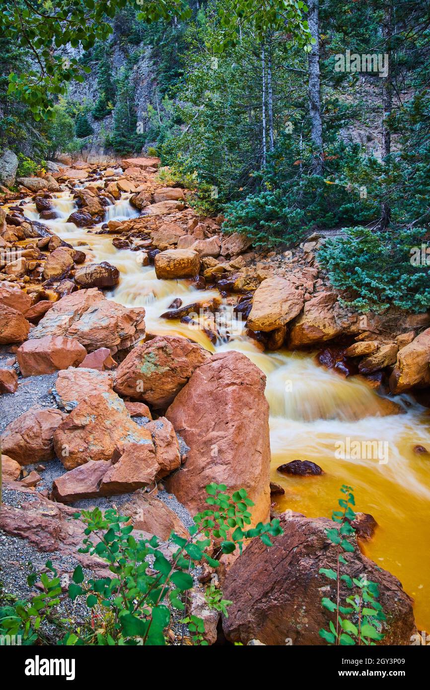 Waterfalls cascading down small river lined with large red rocks Stock ...