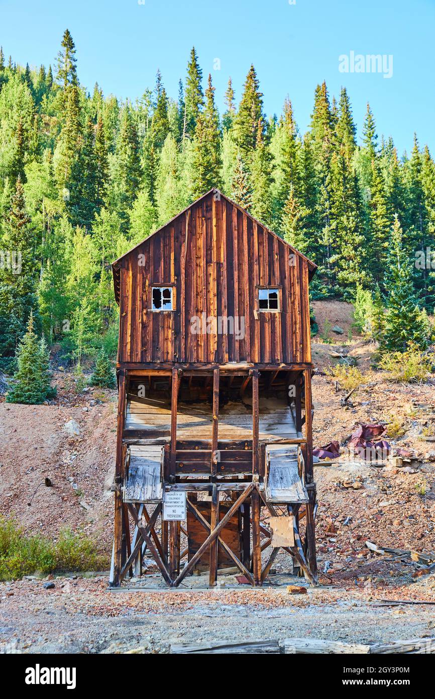 Old empty log mining structure with wall of mountains Stock Photo - Alamy