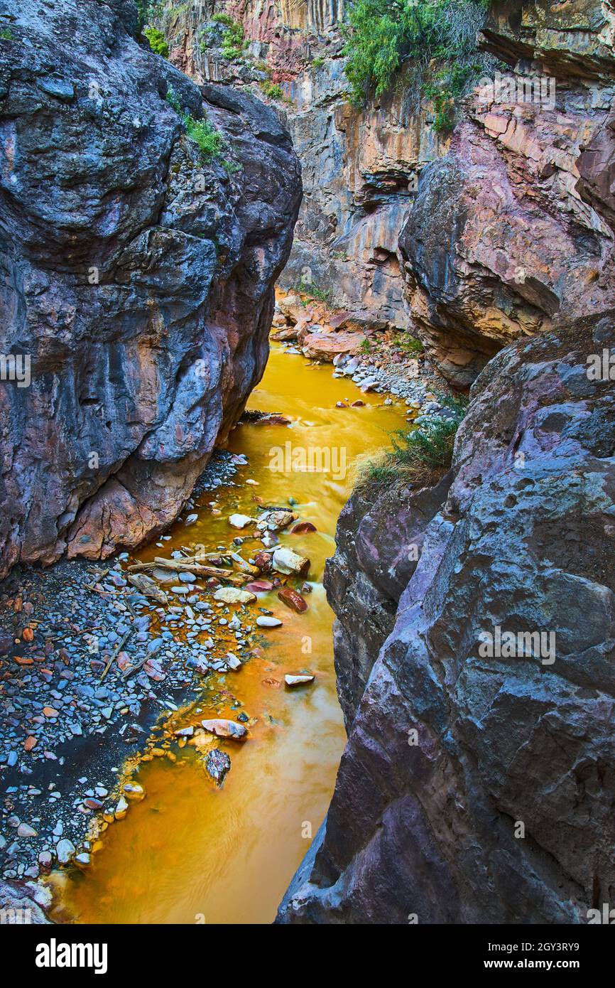 Deep canyon of large colorful rocks and yellow river water Stock Photo ...