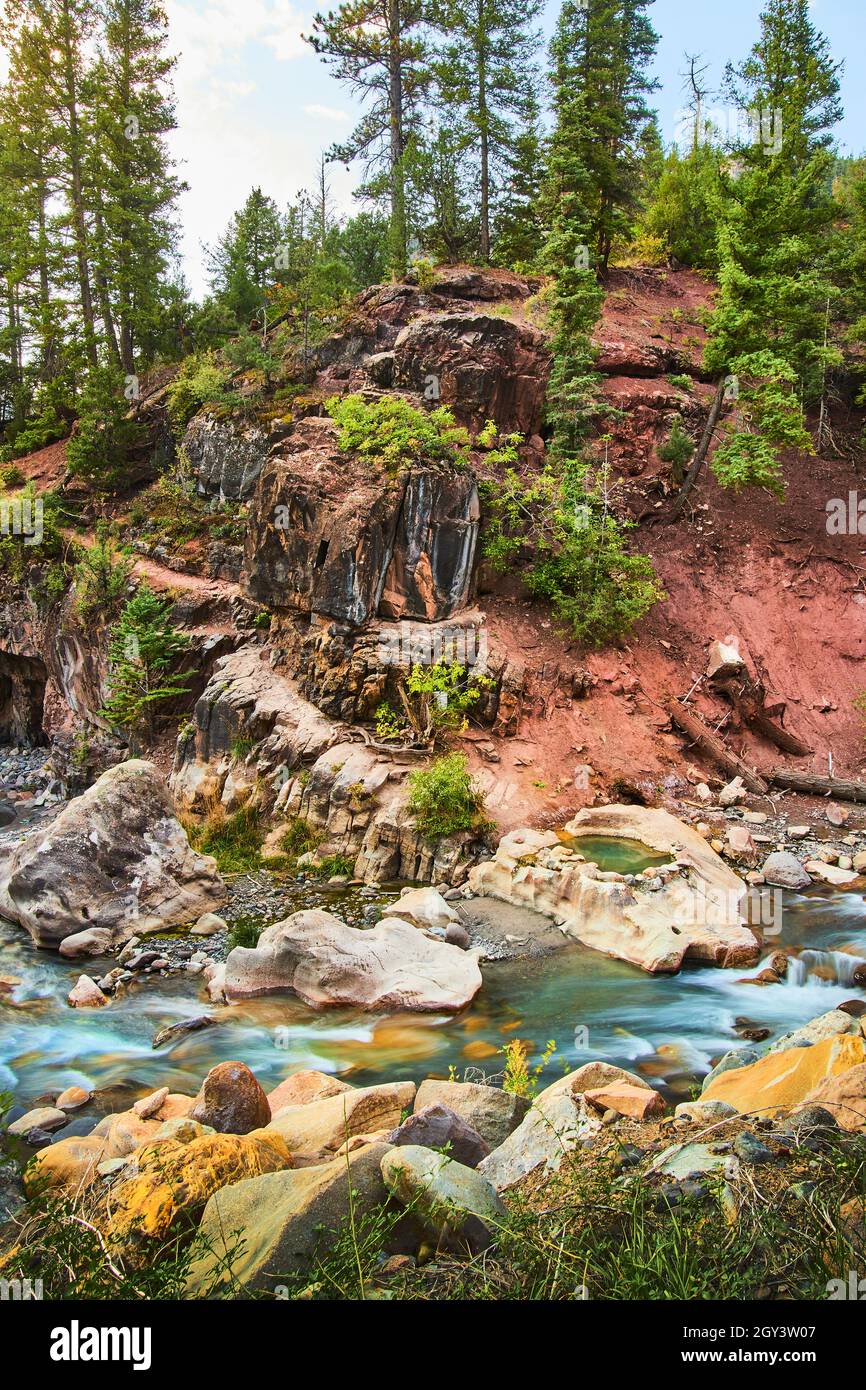 Secret hippie hot spring by river with trail up red mountains Stock ...
