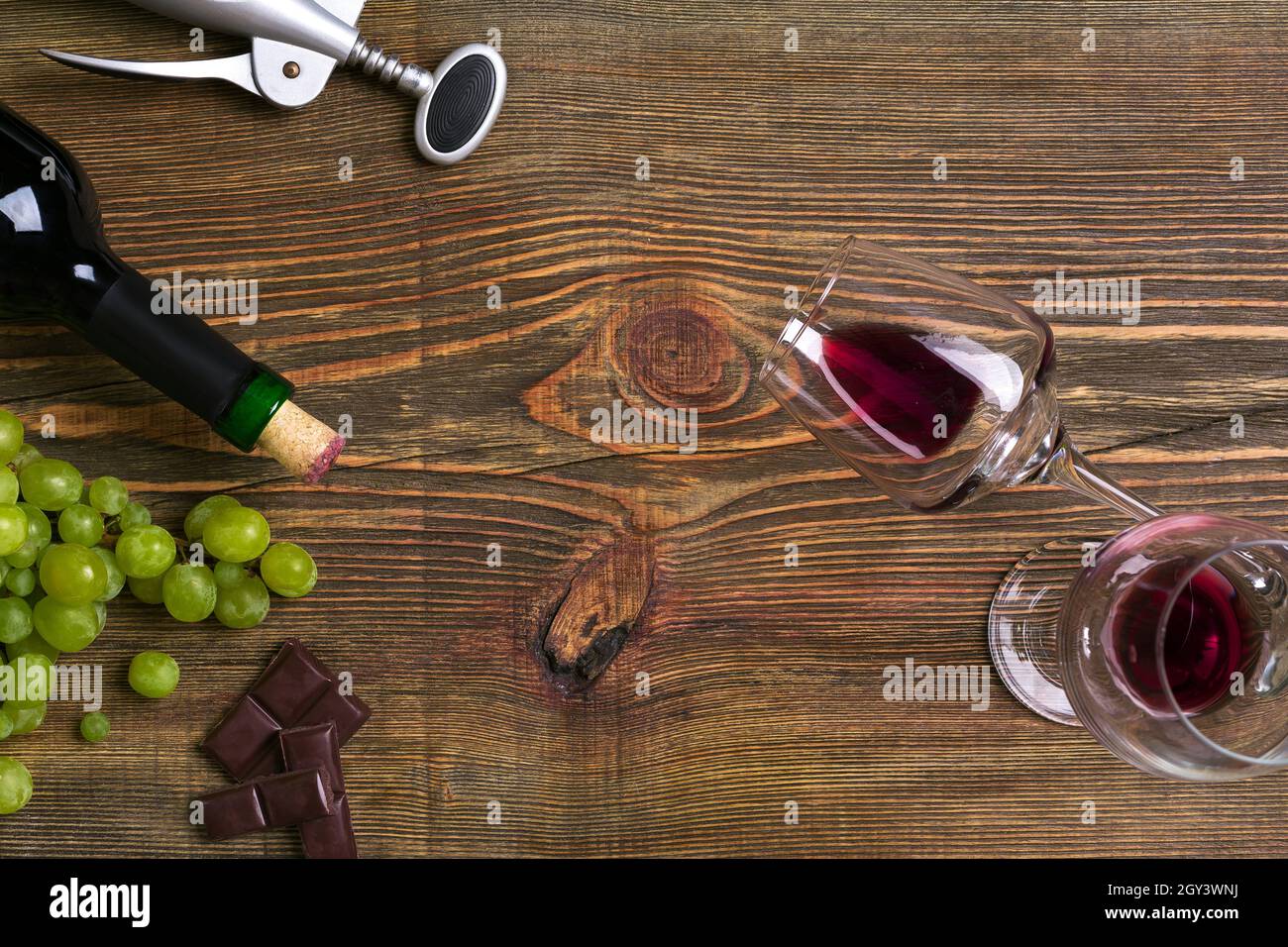 Red wine bottle, grape, chocolate and glasses over wooden table. Top ...