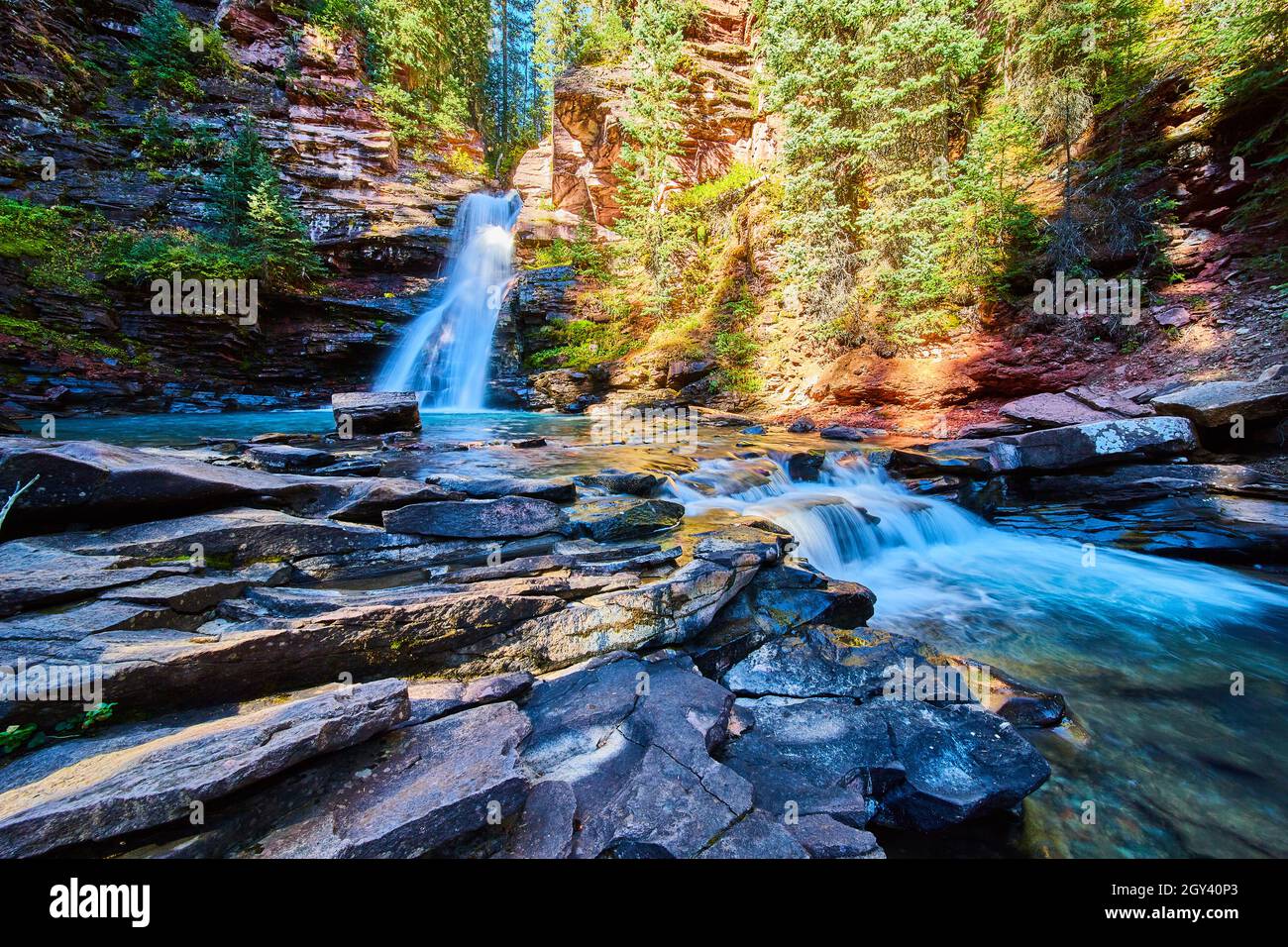 Vibrant blue water and waterfall in gorge with tiers of rock Stock ...
