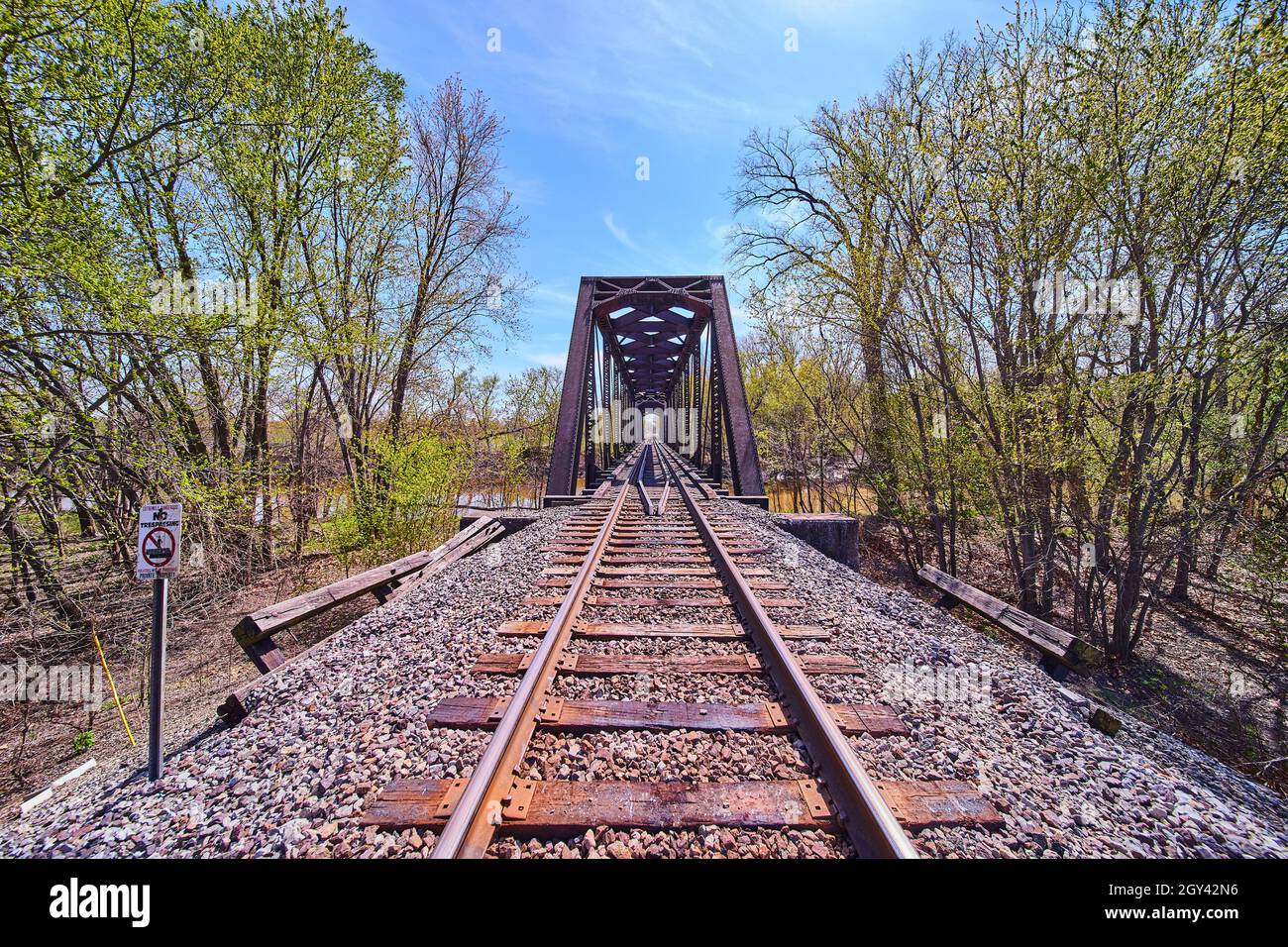 Train tracks in forest leading to large bridge over water Stock Photo ...