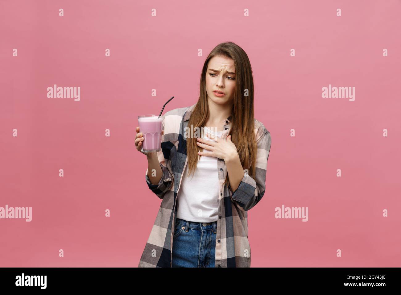 Disappointed young woman drinking smoothie juice. Isolated portrait ...