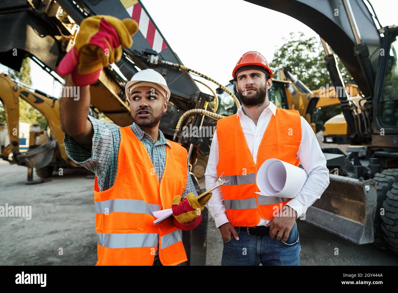 Two men engineers discussing their work standing against construction ...
