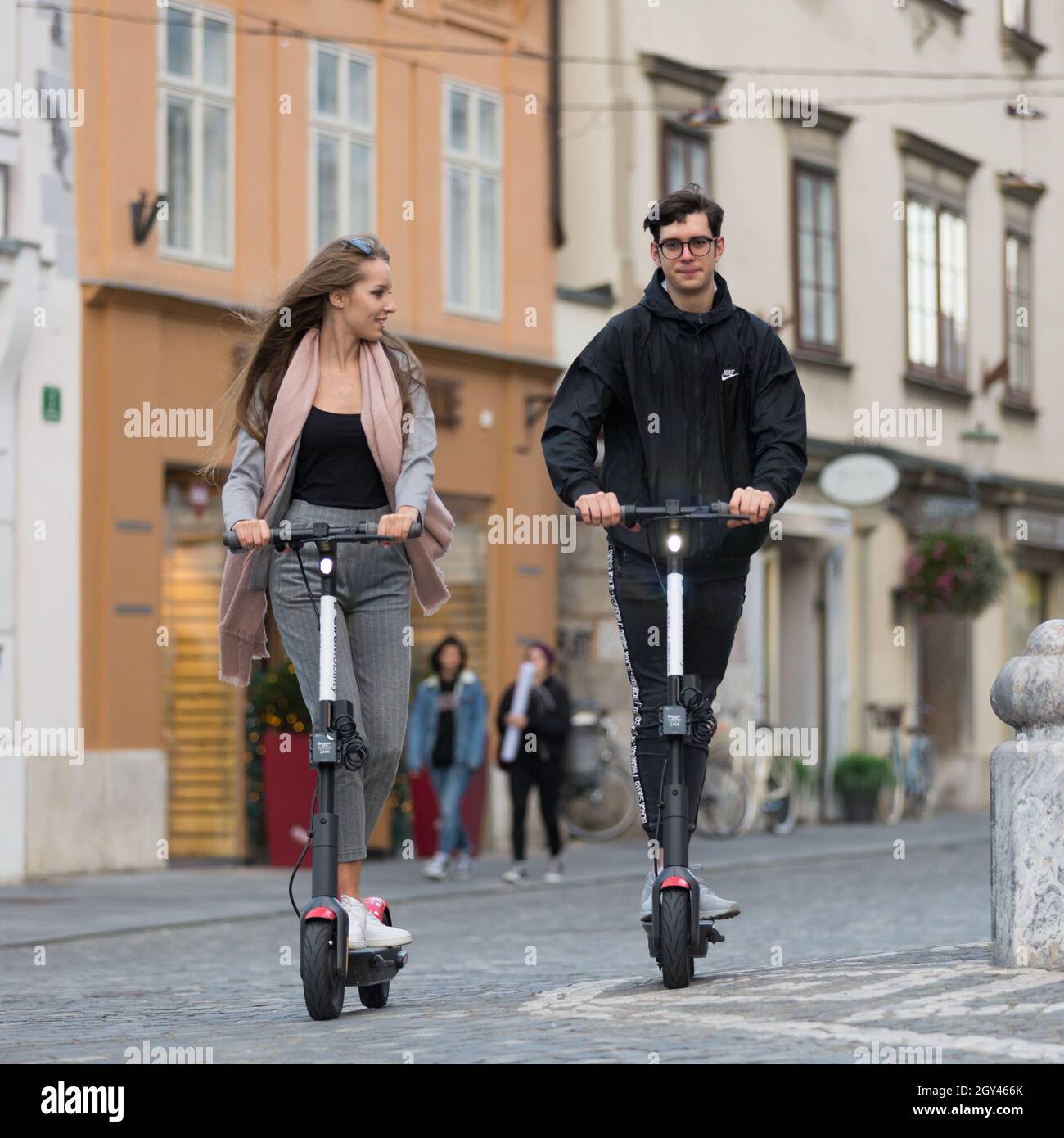 Trendy fashinable teenagers riding public rental electric scooters in ...