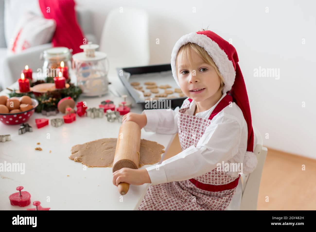 Cute blond child, boy and his mom, baking christmas cookies at home ...