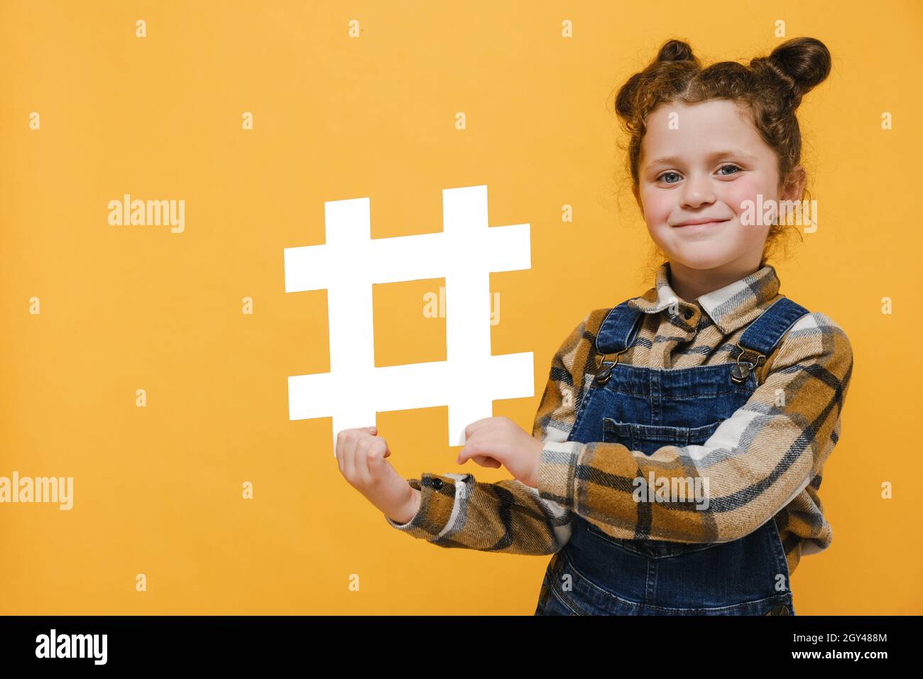 Happy cute girl child holding big white hashtag symbol, smiling looking ...