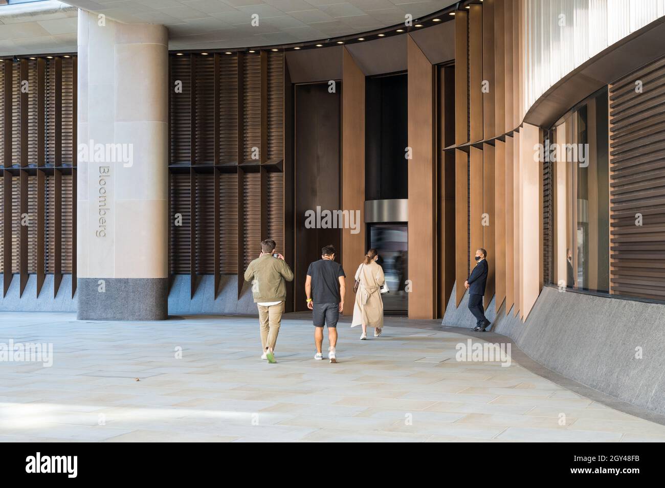 Two men and a woman approach the main entrance to the Bloomberg ...